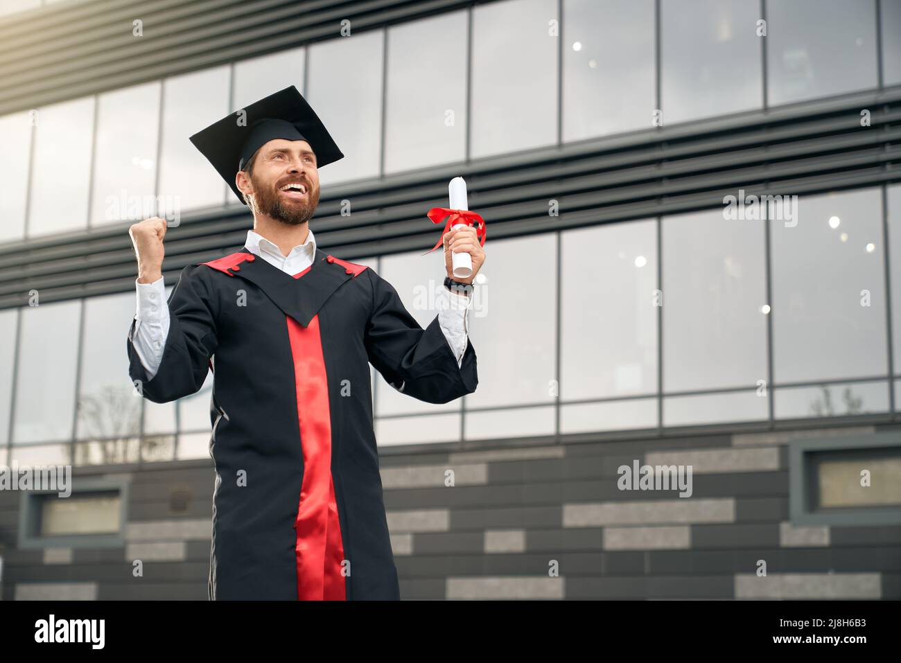 Front view of student wearing mortarboard and graduate gown graduating ...