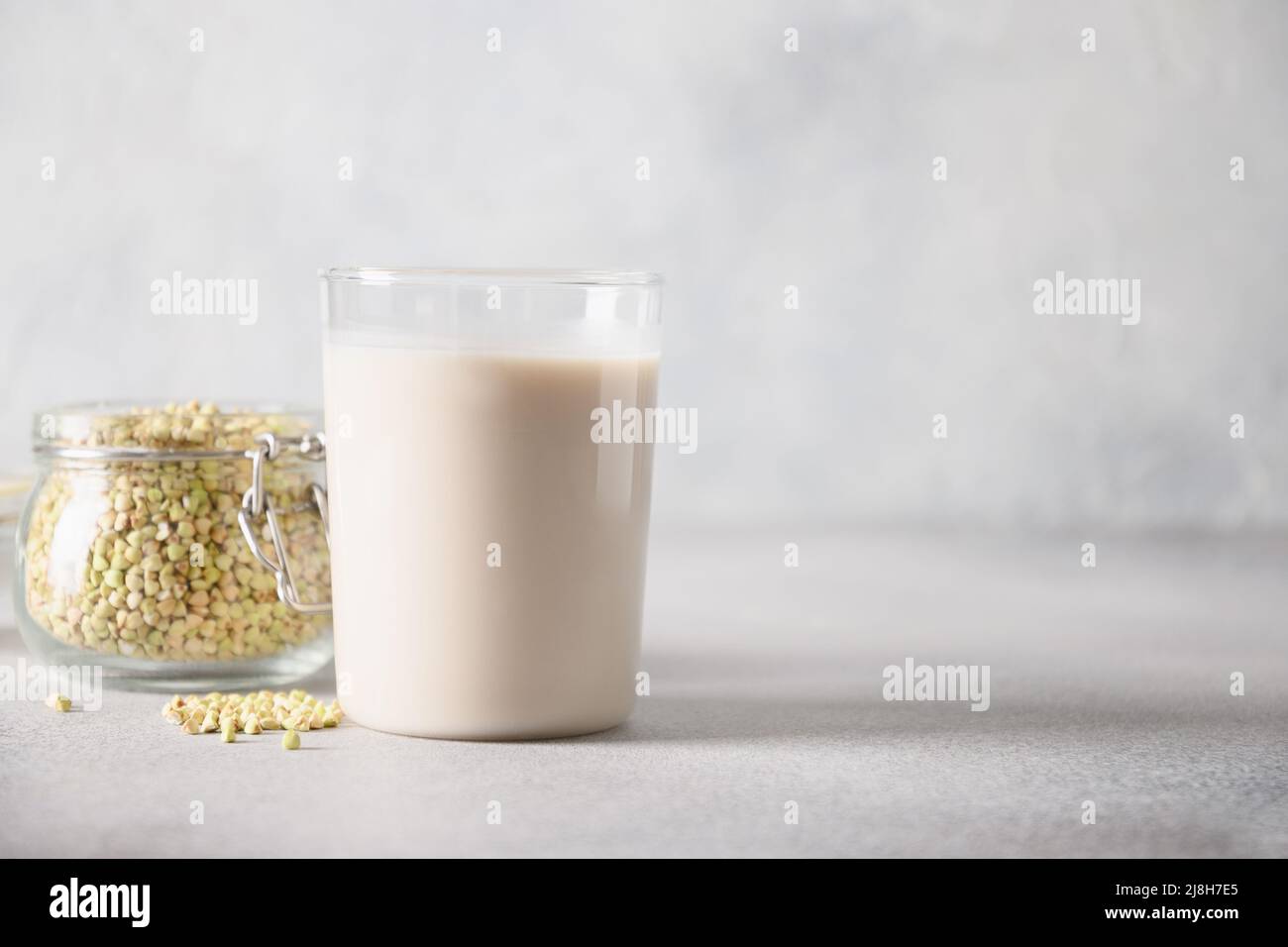 Vegan green buckwheat milk in glass on gray background. Close up. Plant ...