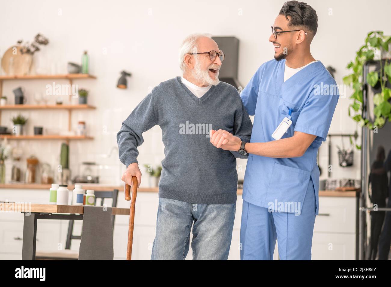 Patient leaning on the cane supported by a young nurse Stock Photo - Alamy