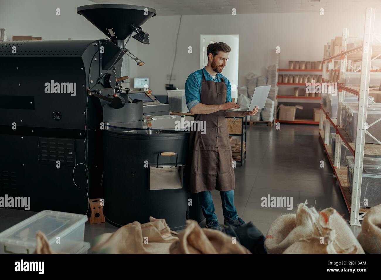 Business owner of coffee factory working laptop on background of coffee ...