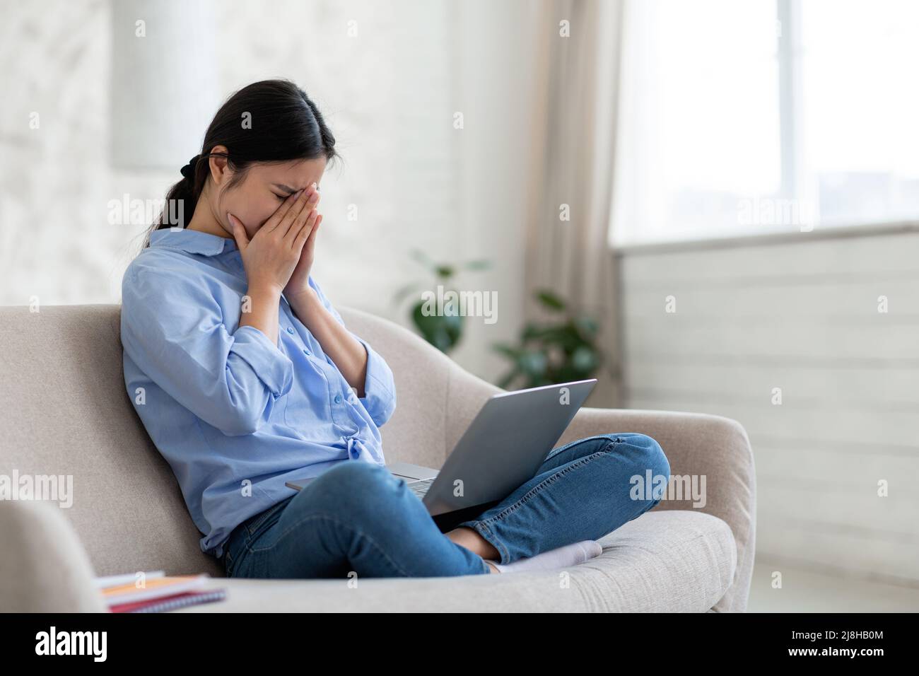 Upset asian woman with notebook on lap crying Stock Photo - Alamy