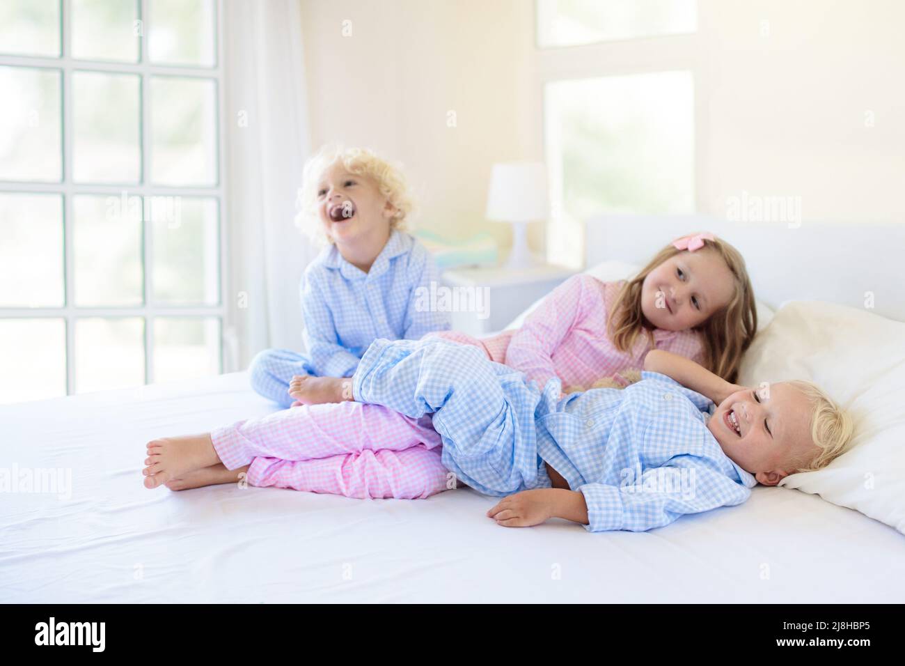 Kids playing in parents bed. Children wake up in sunny white bedroom ...