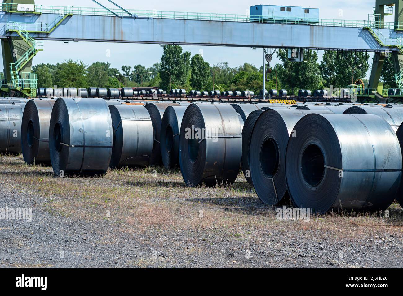 Metal sheets wrapped in large rolls, standing on the loading yard next ...