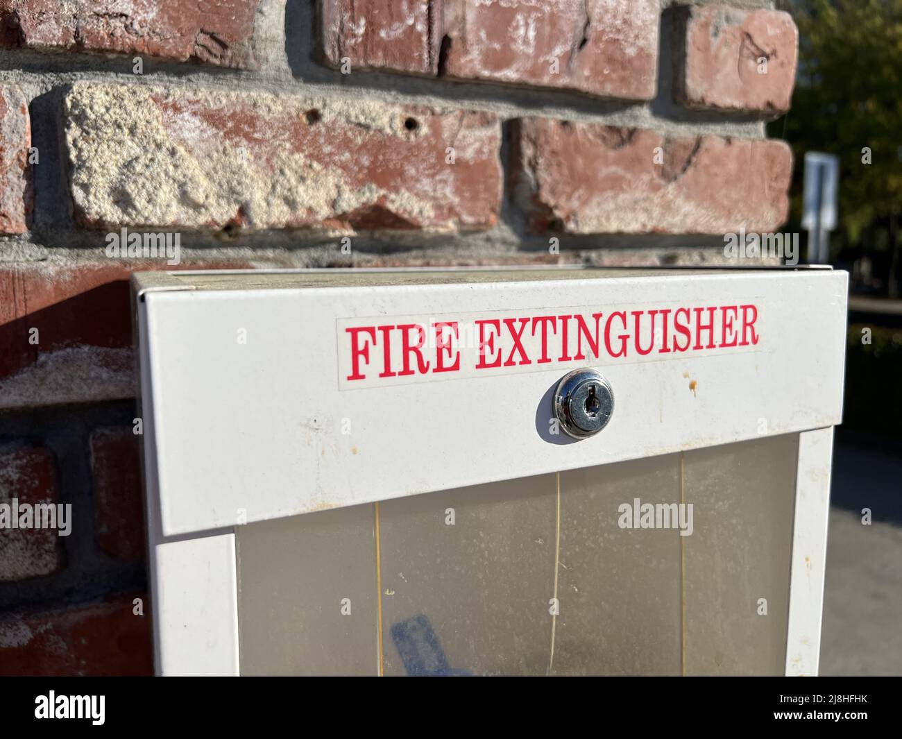 Wall mounted glass compartment for fire extinguisher with text reading ...