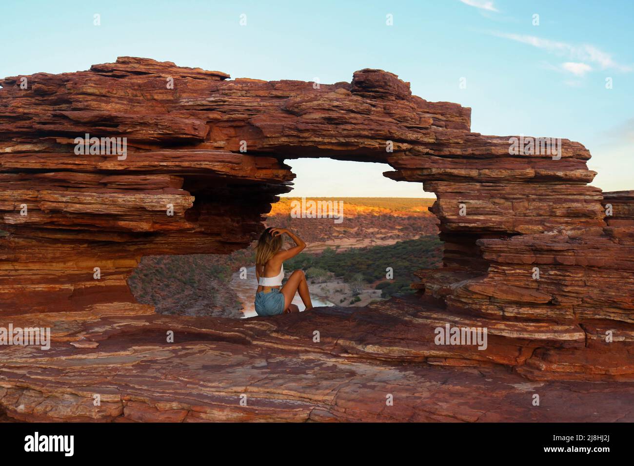 Back portrait of woman in casual clothes at natural red rock window ...