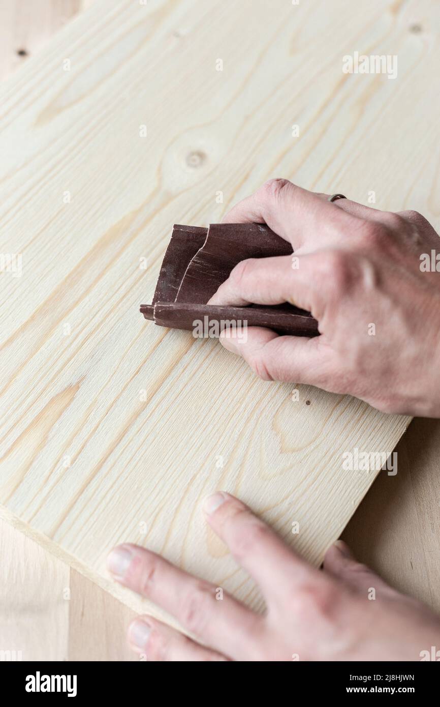 Sanding boards by hand. Sanding with abrasive paper Stock Photo - Alamy