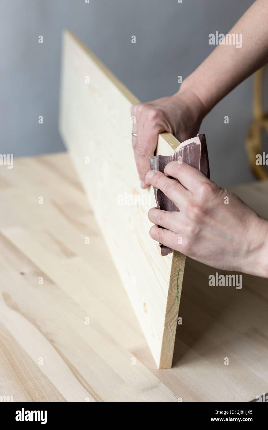 Sanding boards by hand. Sanding with abrasive paper Stock Photo - Alamy