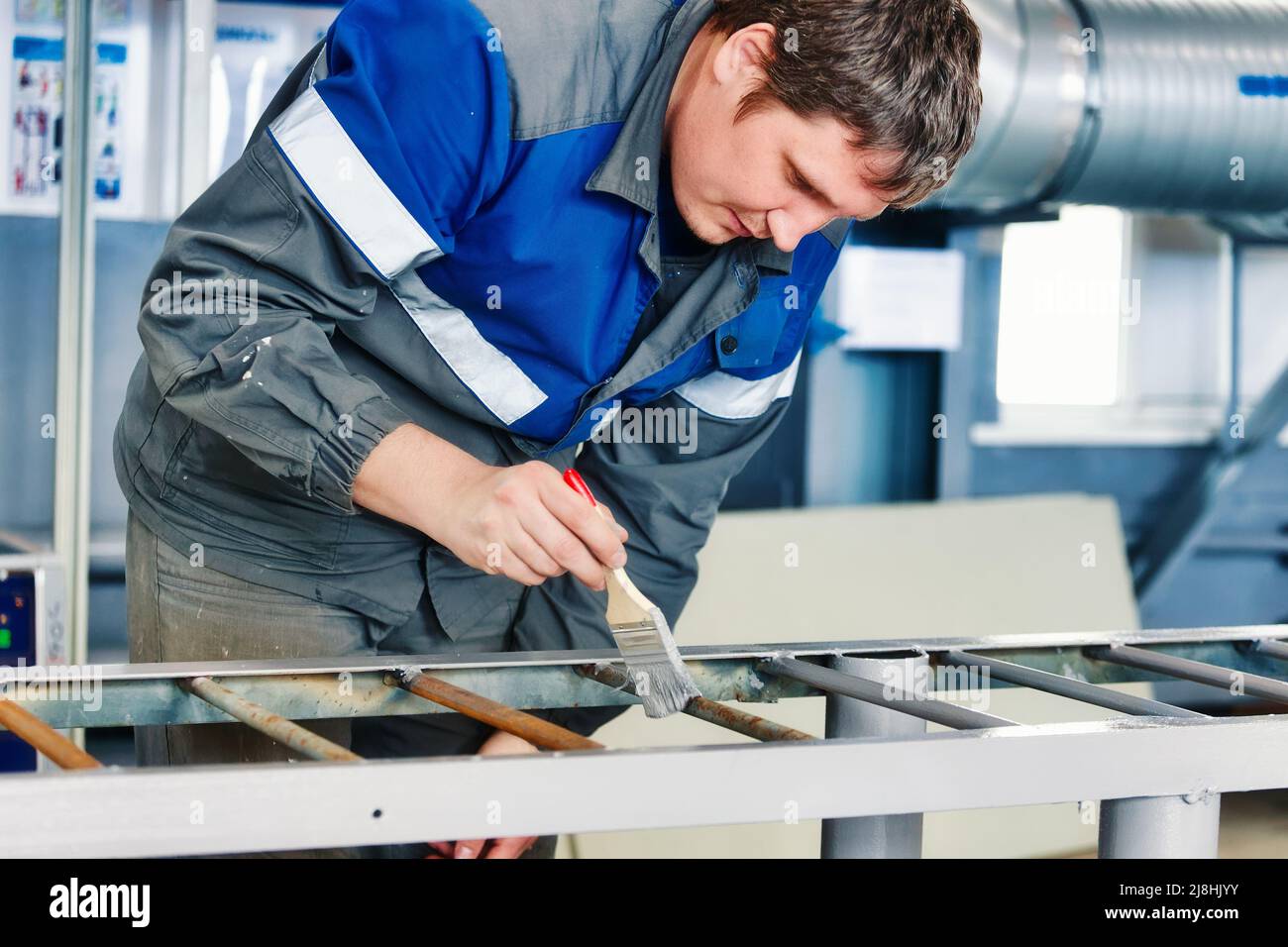 Painter of 30-40 years of Caucasian appearance paints metal structure ...