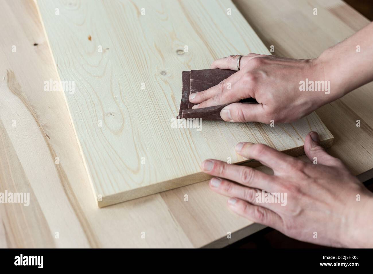 Sanding boards by hand. Sanding with abrasive paper Stock Photo - Alamy