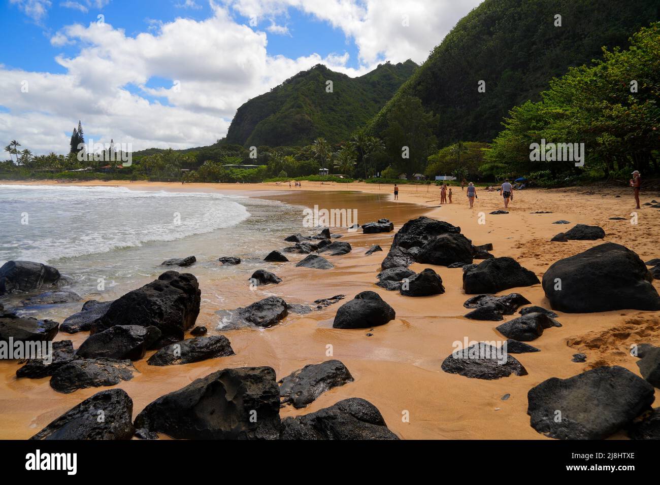 Black rocks stranded on the sand of Cannon's Beach next to Haena Beach ...