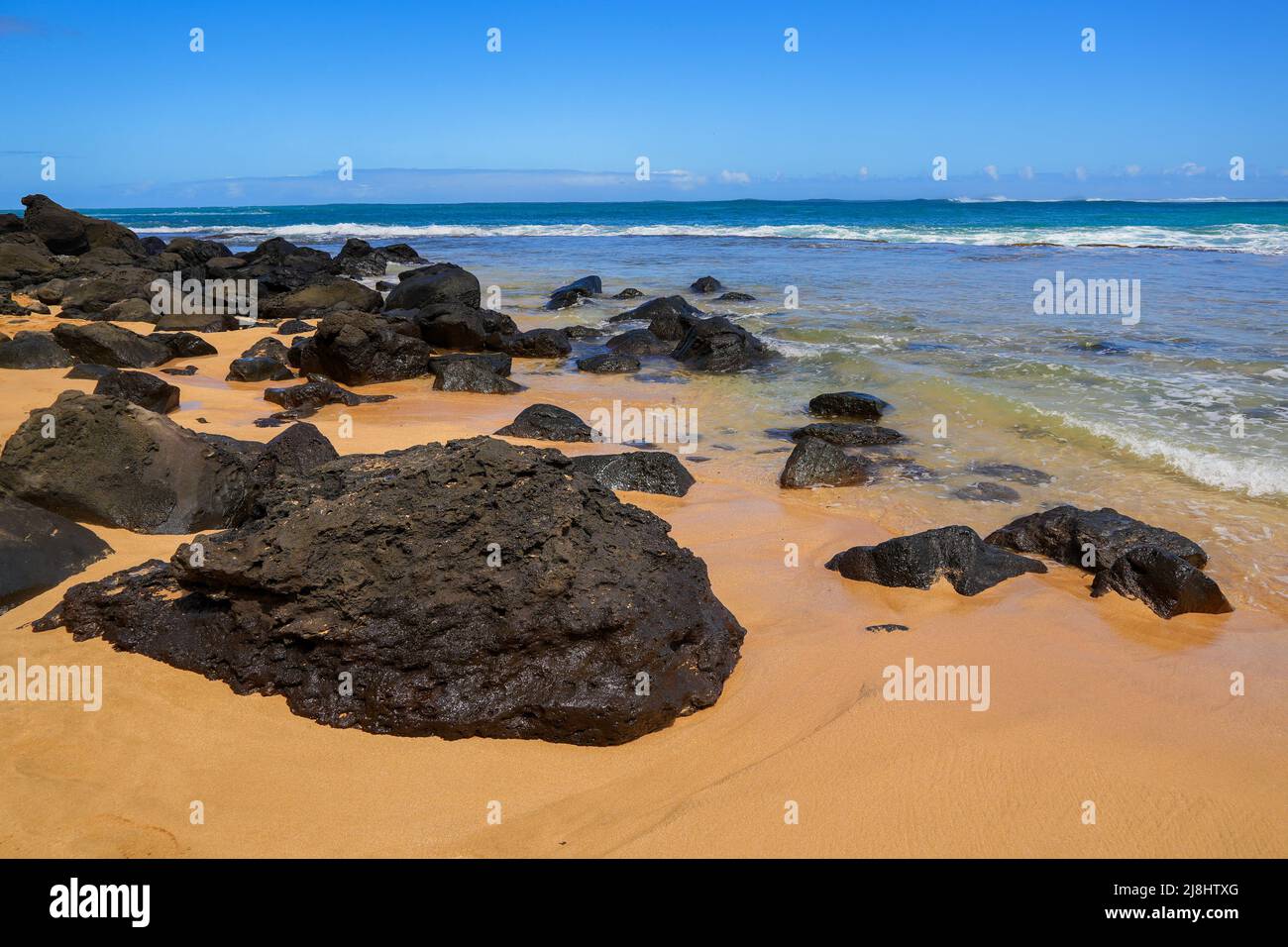 Black rocks stranded on the sand of Cannon's Beach on the North Shore ...