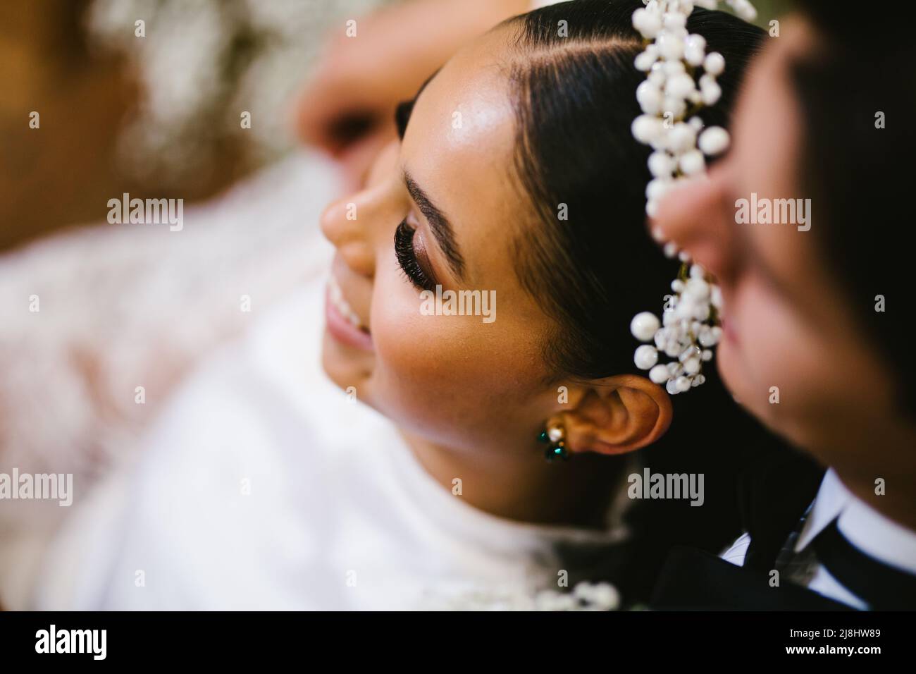 Latina bride and multiracial groom snuggle after the wedding ceremony ...