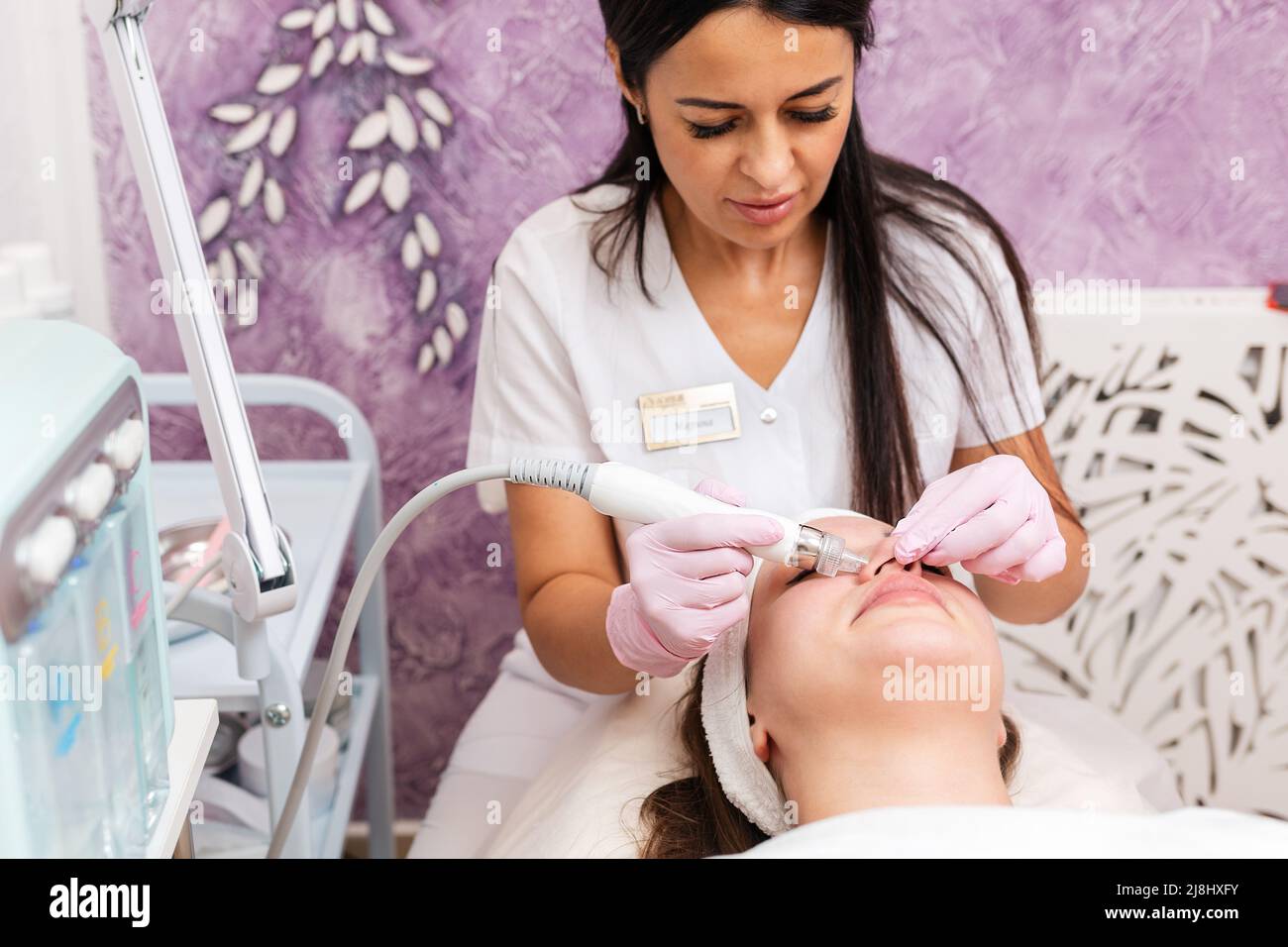 Beauty salon. The cosmetologist makes a water peeling procedure for the ...