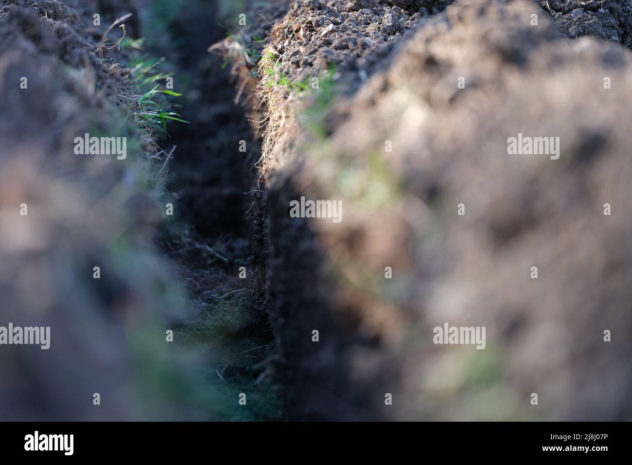 Trench in ground for electrical or internet cable at construction site ...