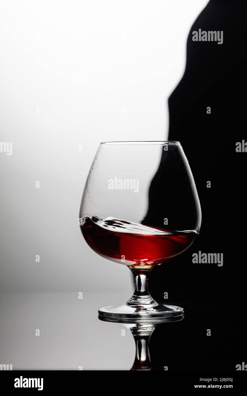 Splash of brandy in a snifter glass. Copy space Stock Photo - Alamy