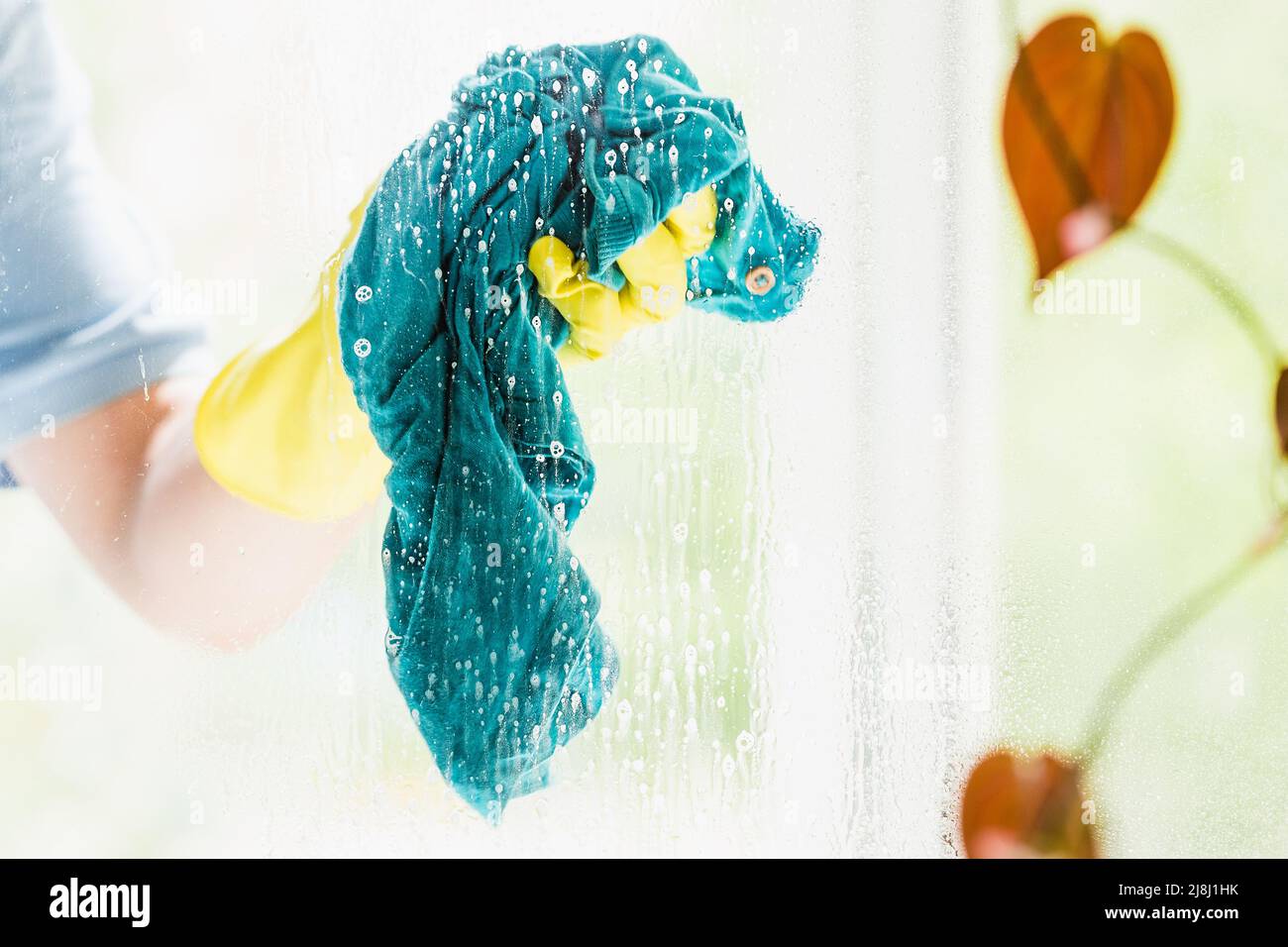 Male hands cleaning house window glass with blue rag. Doing home chores ...