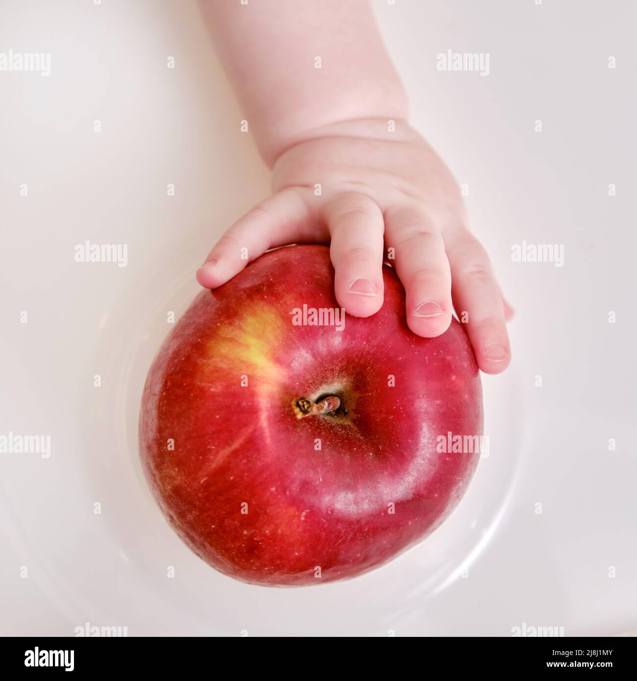 Baby hand and red apple fruit, close-up. Children fingers and an object ...