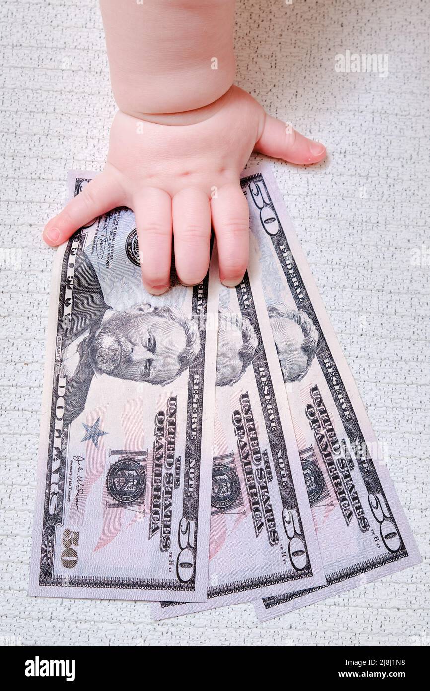 Baby hand and money US dollars, close-up. Children fingers and an ...