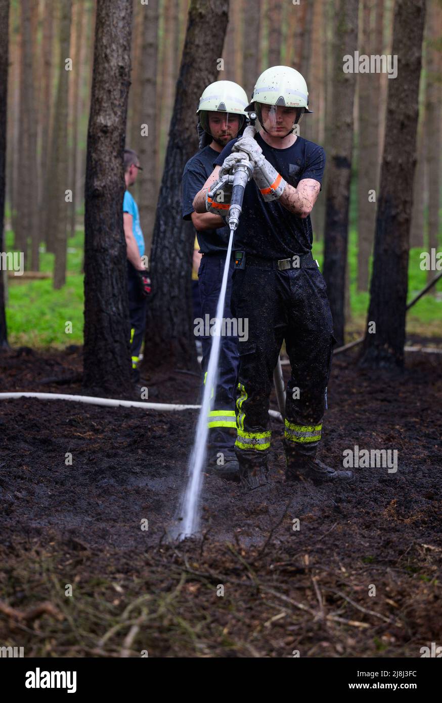 Deutsch Evern, Germany. 16th May, 2022. Firefighters extinguish embers ...