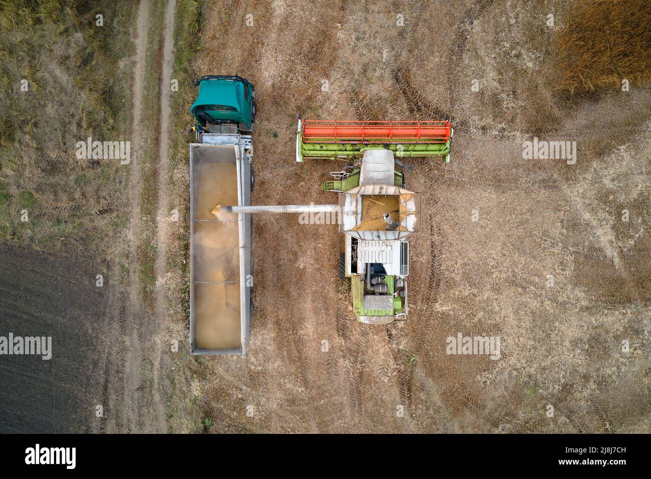 Aerial view of combine harvester unloading grain in cargo trailer ...