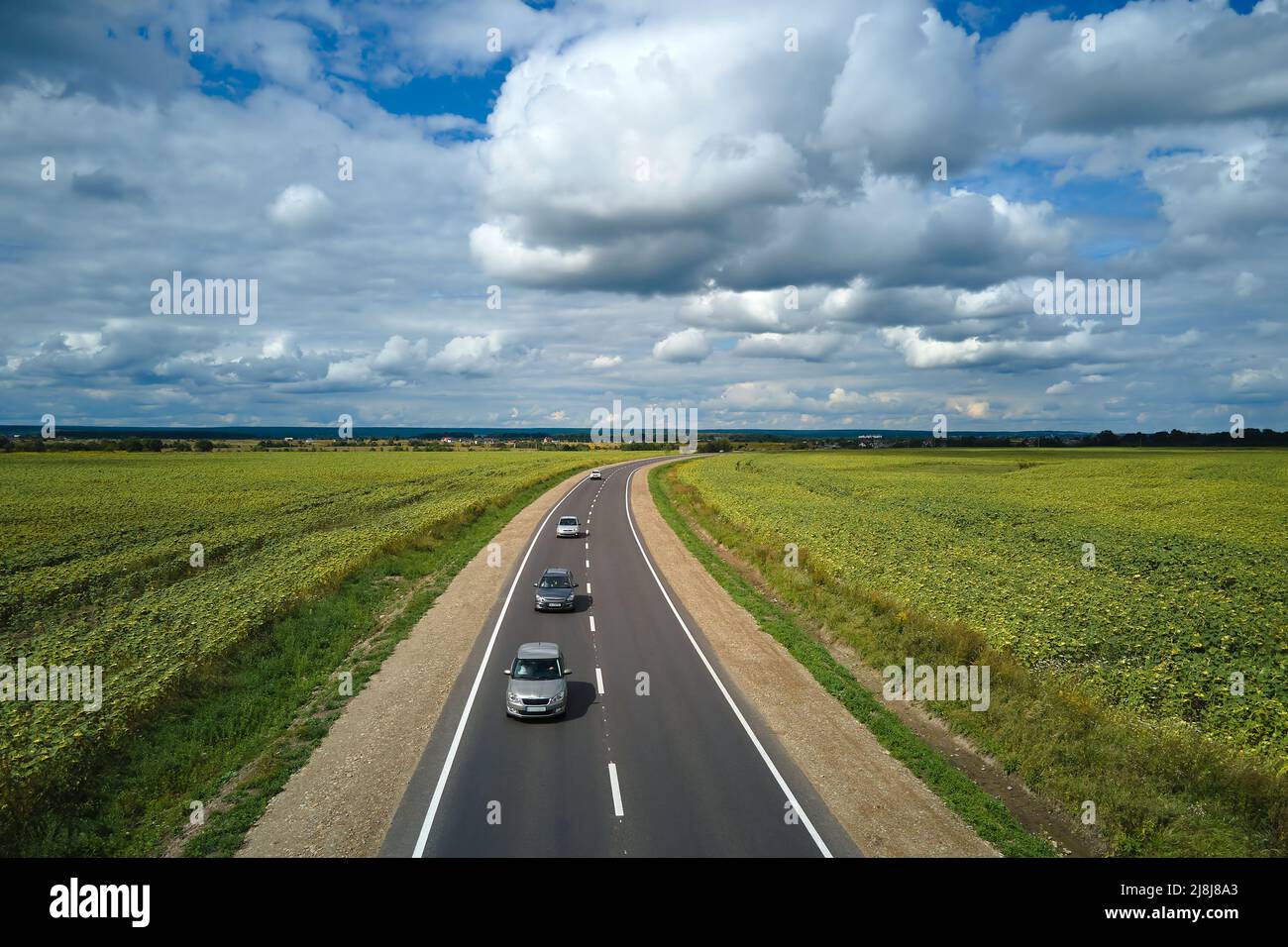 Aerial view of intercity road between green agricultural fields with ...