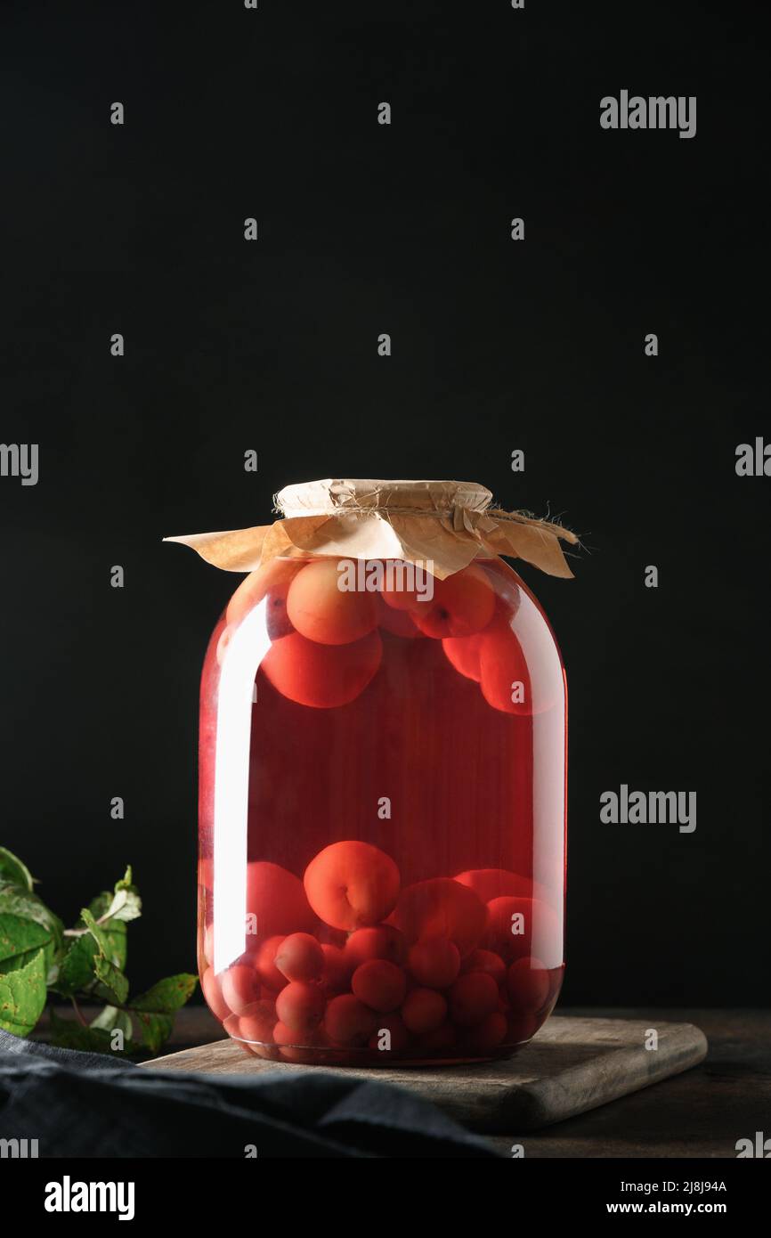 Homemade fruits compote in large glass jar isolated on black background ...