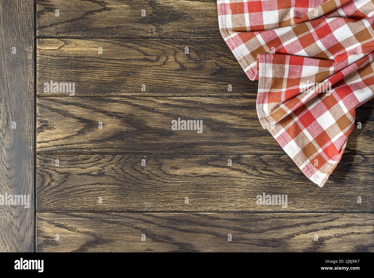 Checkered napkin at right top corner of oak table background, top view ...