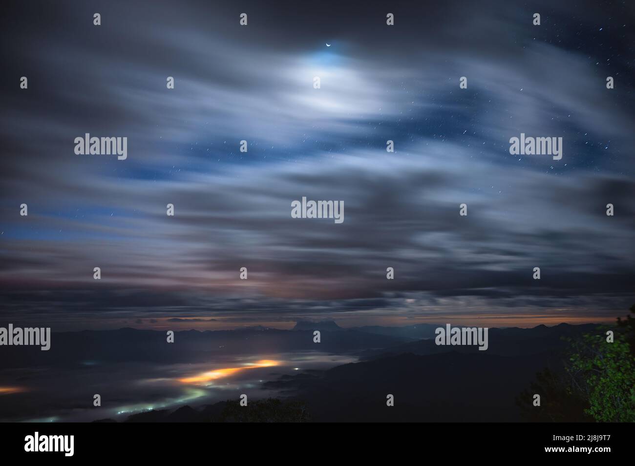 Landscape of cloudy blowing through blue sky with stars and moonlight ...