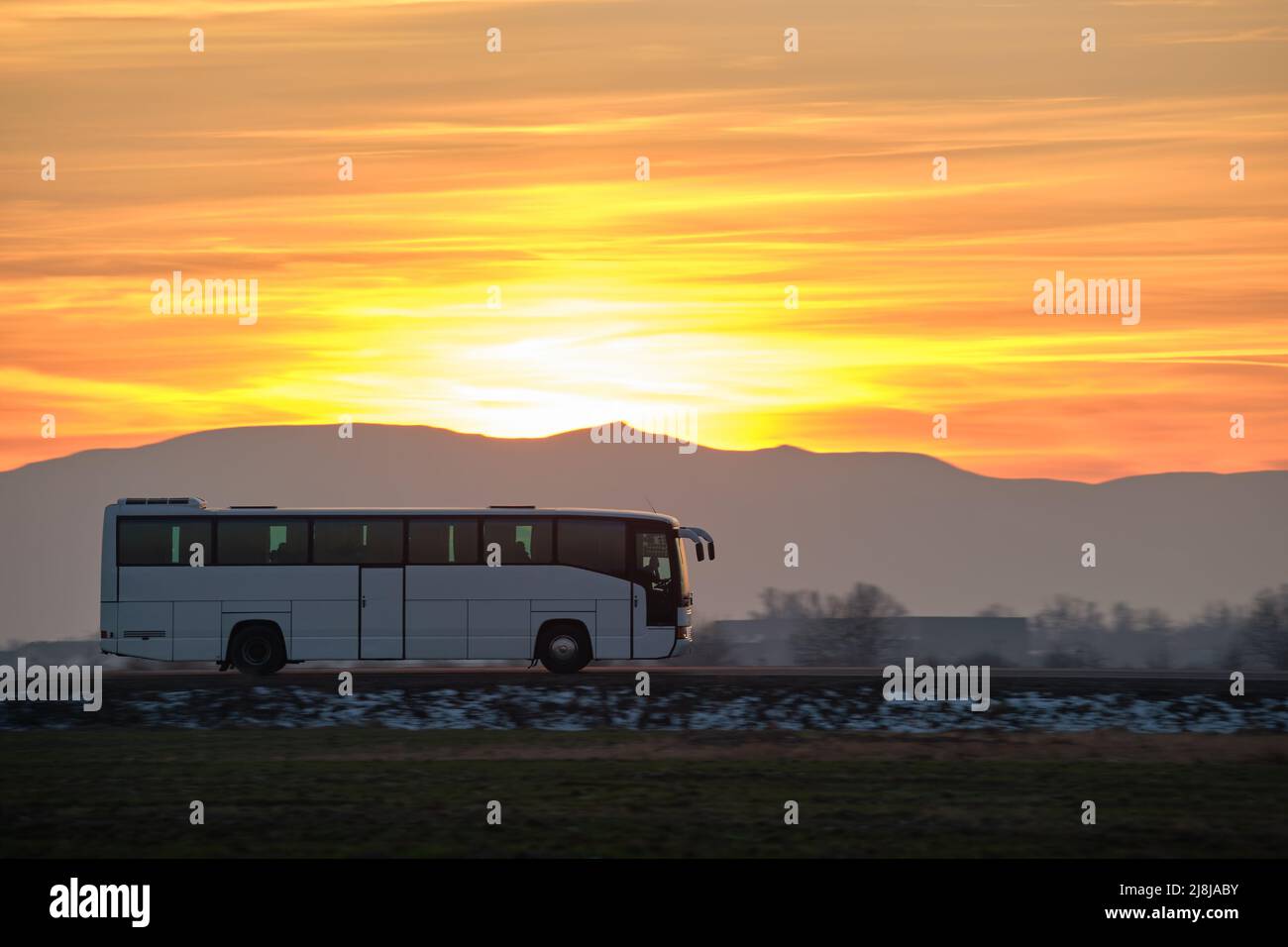 Intercity passenger bus driving on highway road in evening Stock Photo ...
