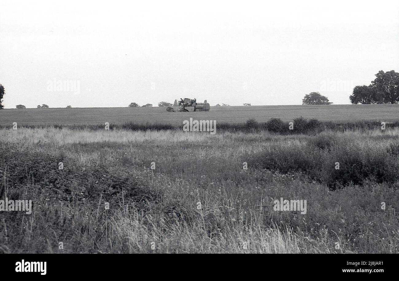 1970, historical, farming, a farmer sitting on a havester machine in a ...