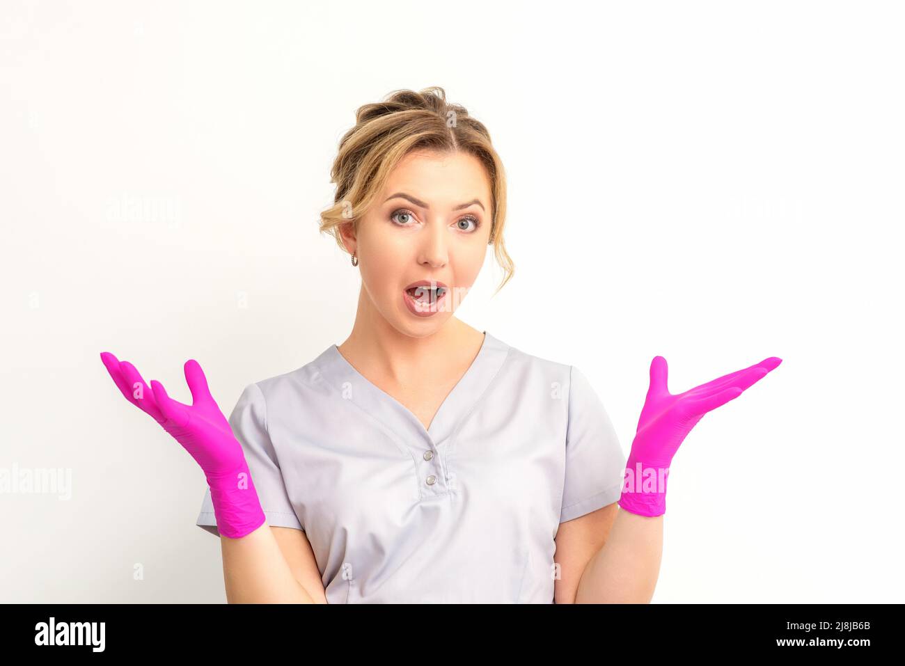 Body language. Young surprised Caucasian woman doctor wearing gloves ...