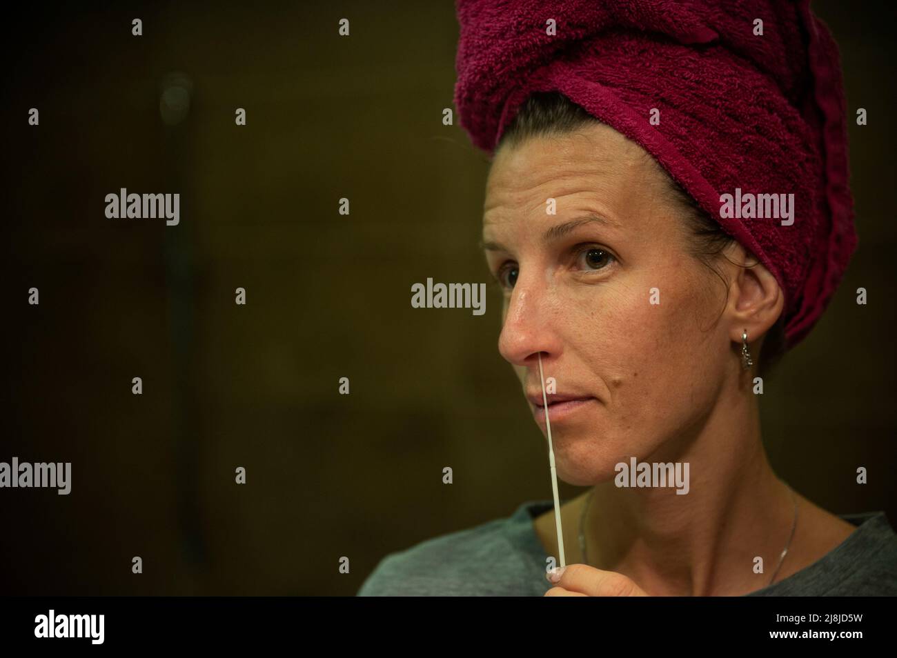 Young woman with a towel rolled on her wet hair taking a nasal sample ...