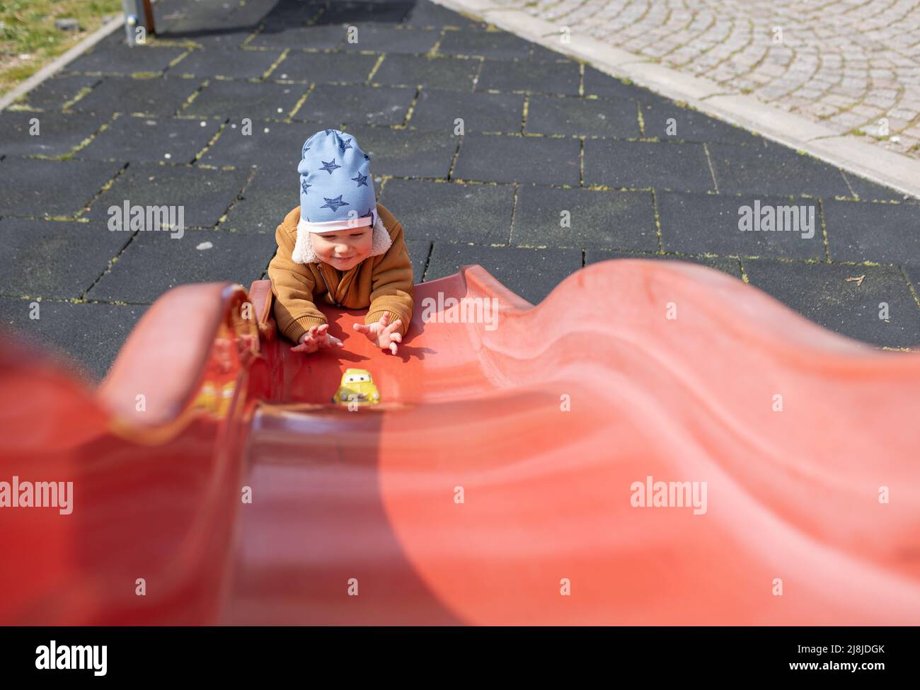 Cheerful funny little boy in a blue hat and warm clothes plays on the ...