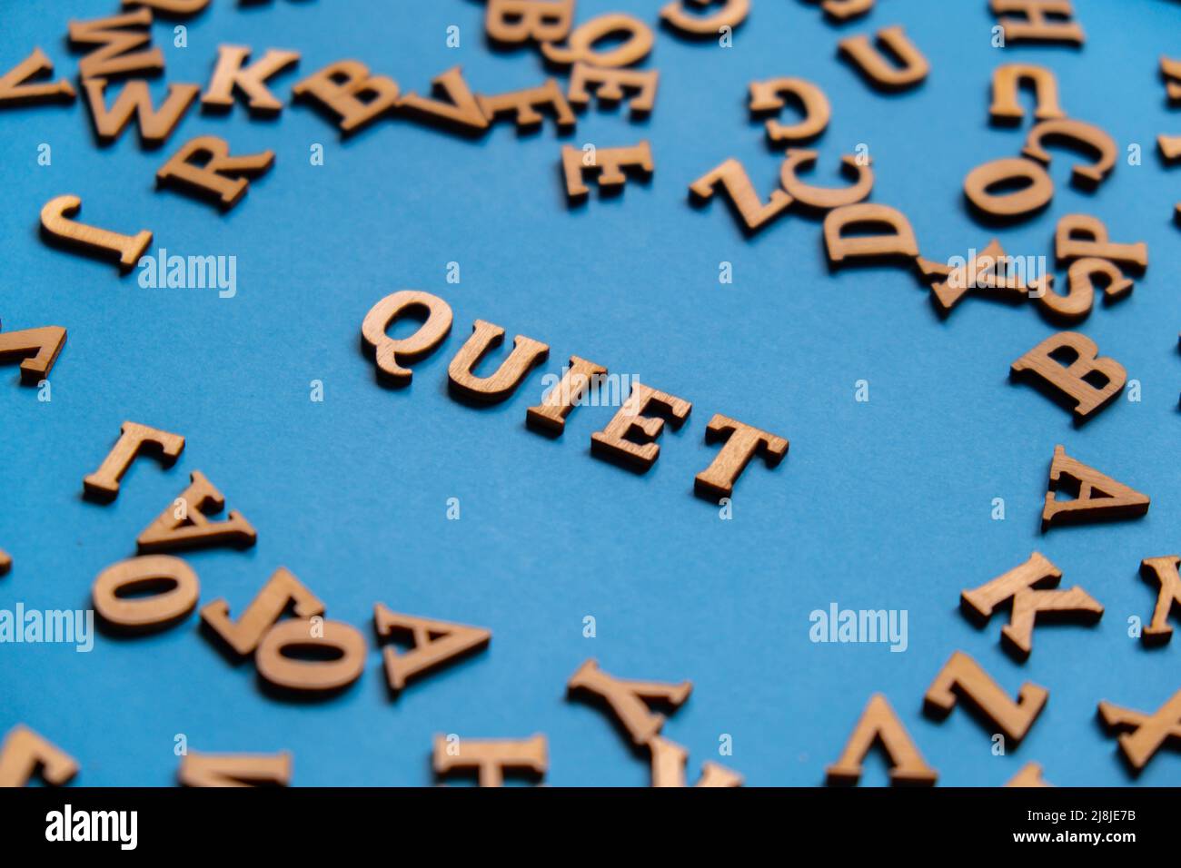 Word QUIET made out of wooden letters on bright blue background ...