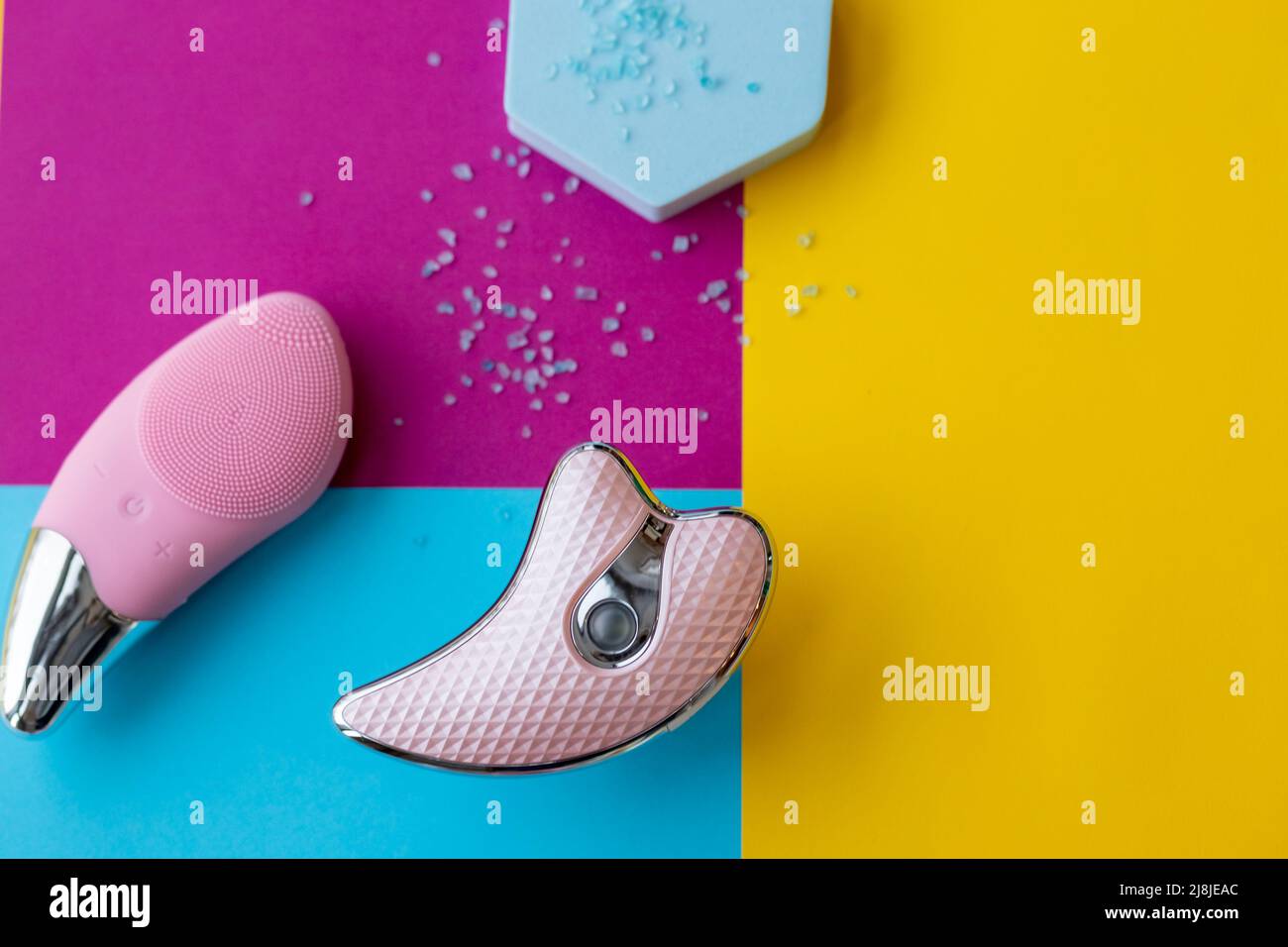 microcurrent facial toning device on pink background with green leaves ...