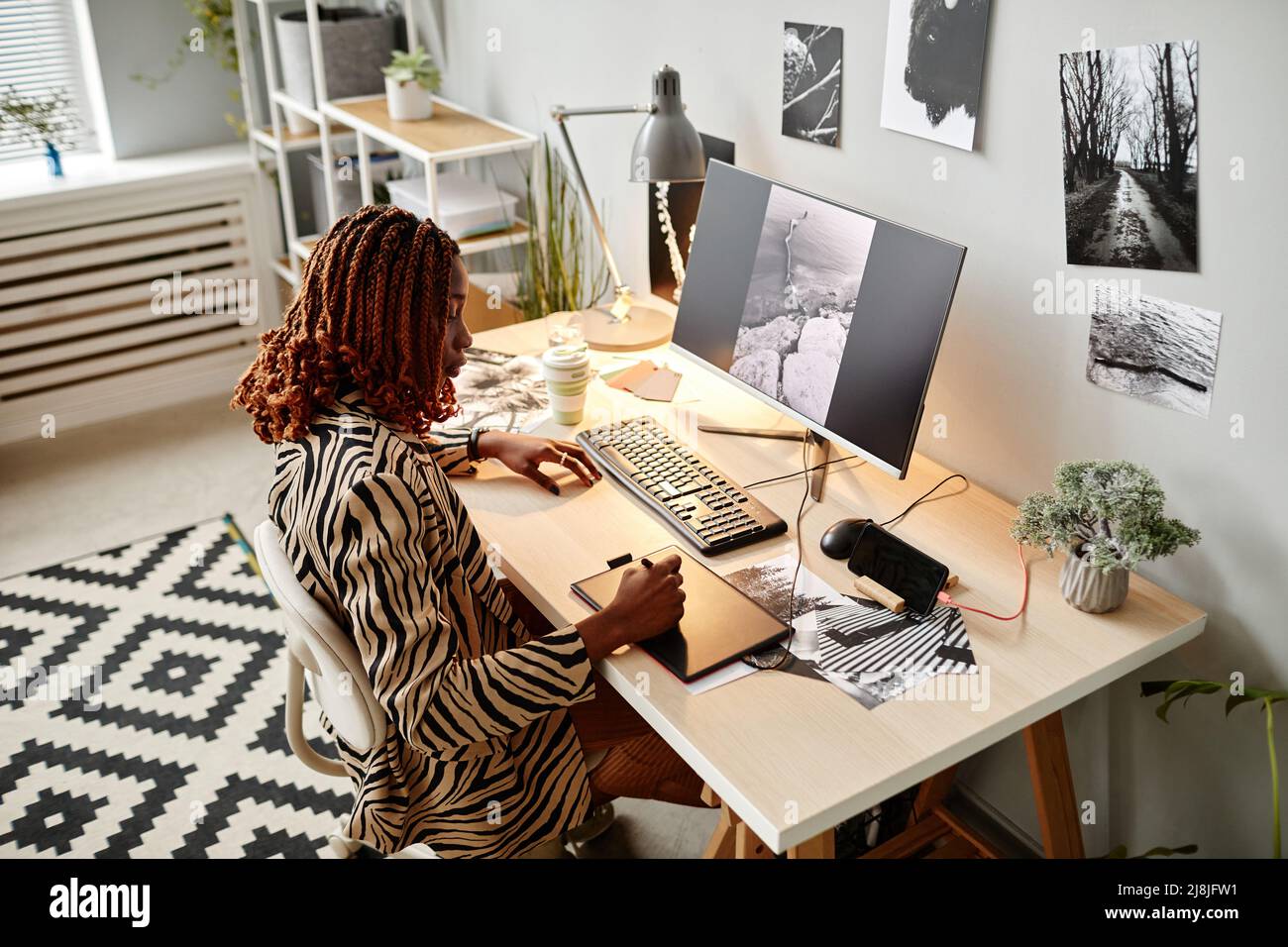 High angle portrait of black female creator editing photographs at home ...