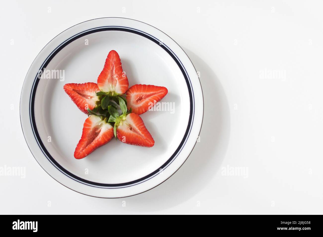 Sliced strawberries in the shape of a star on blue and white plate with ...