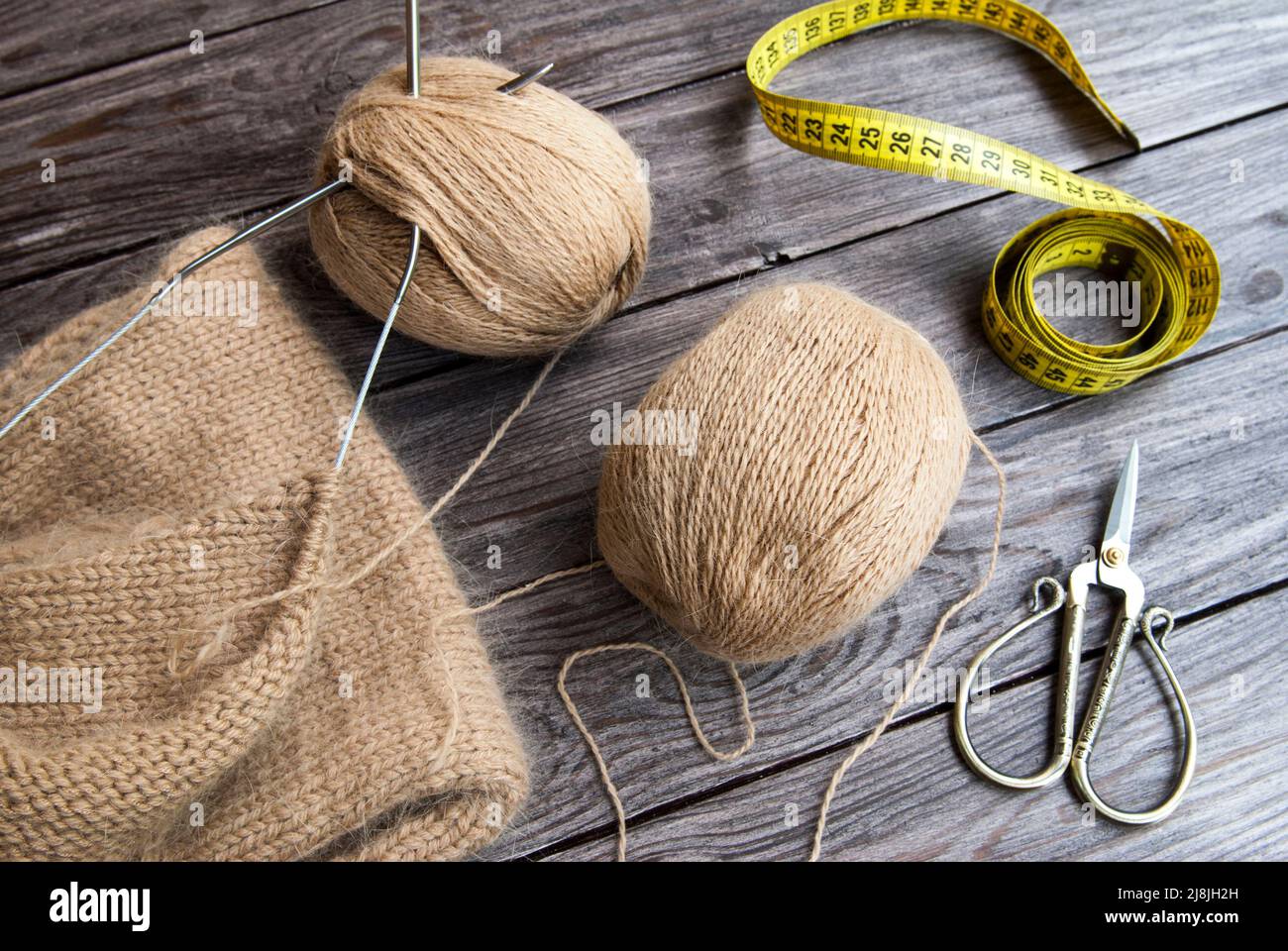 Knitting from wool yarn, scissors and centimeter on wood background ...