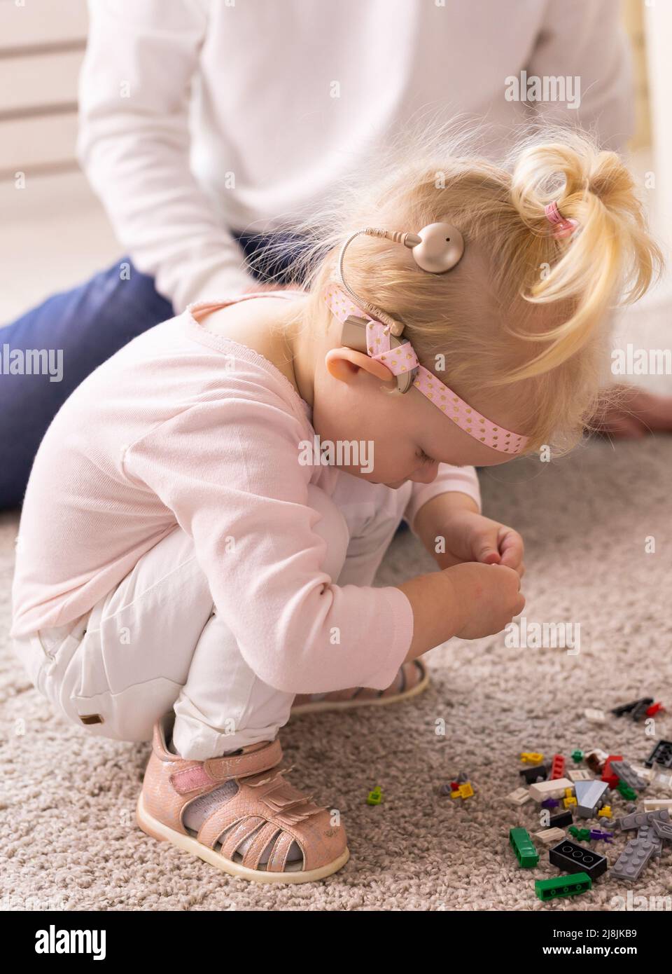 Cochlear implant for baby. Deaf child with hearing aid plays in living ...