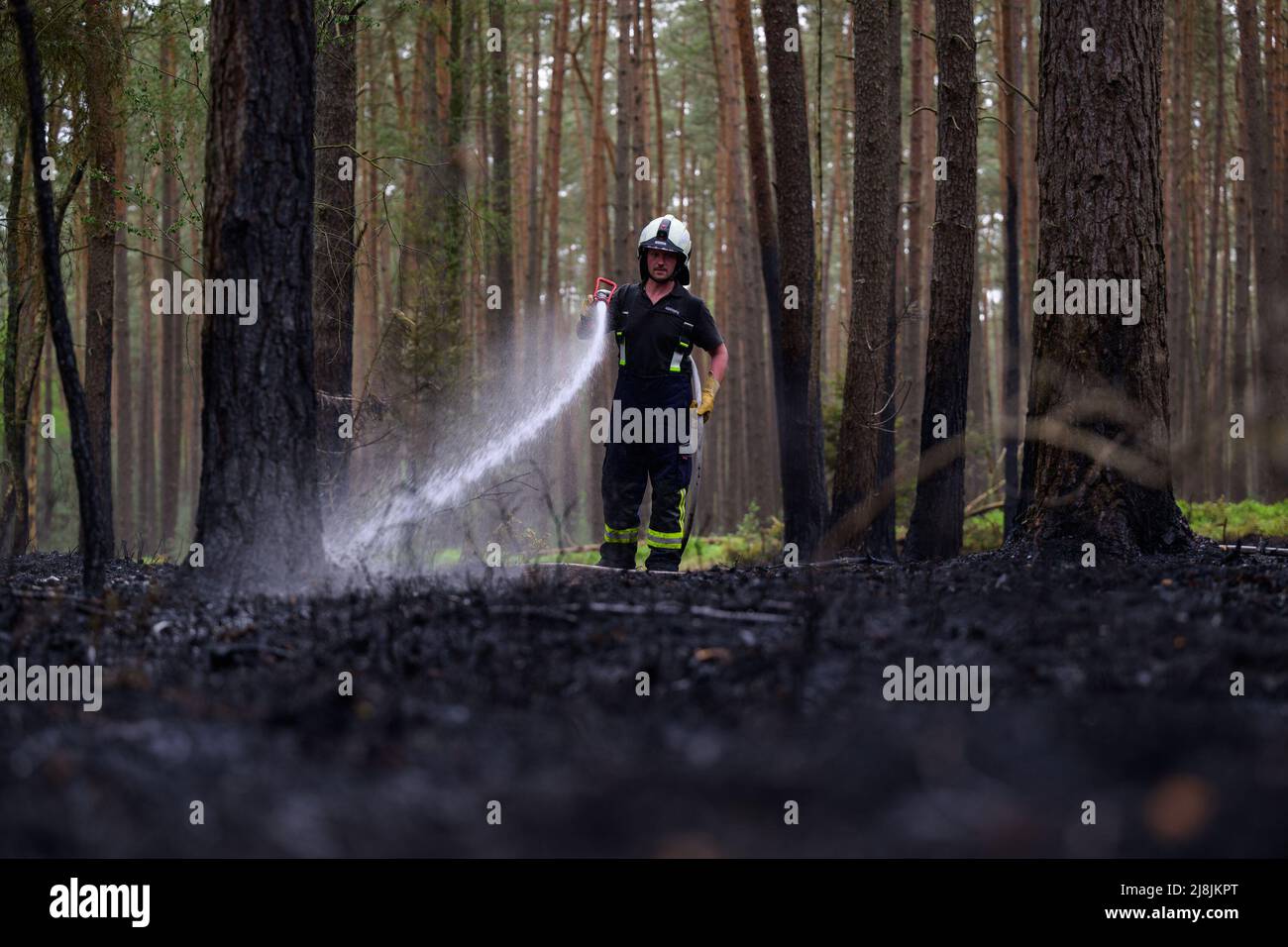 Deutsch Evern, Germany. 16th May, 2022. Firefighters extinguish embers ...