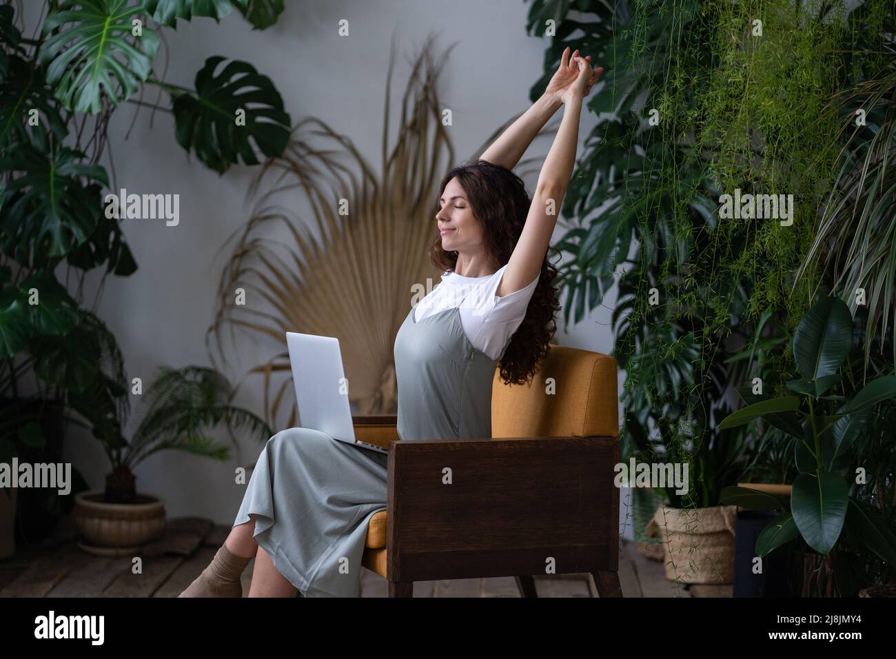Beautiful woman resting after work, sitting on chair in home greenhouse ...
