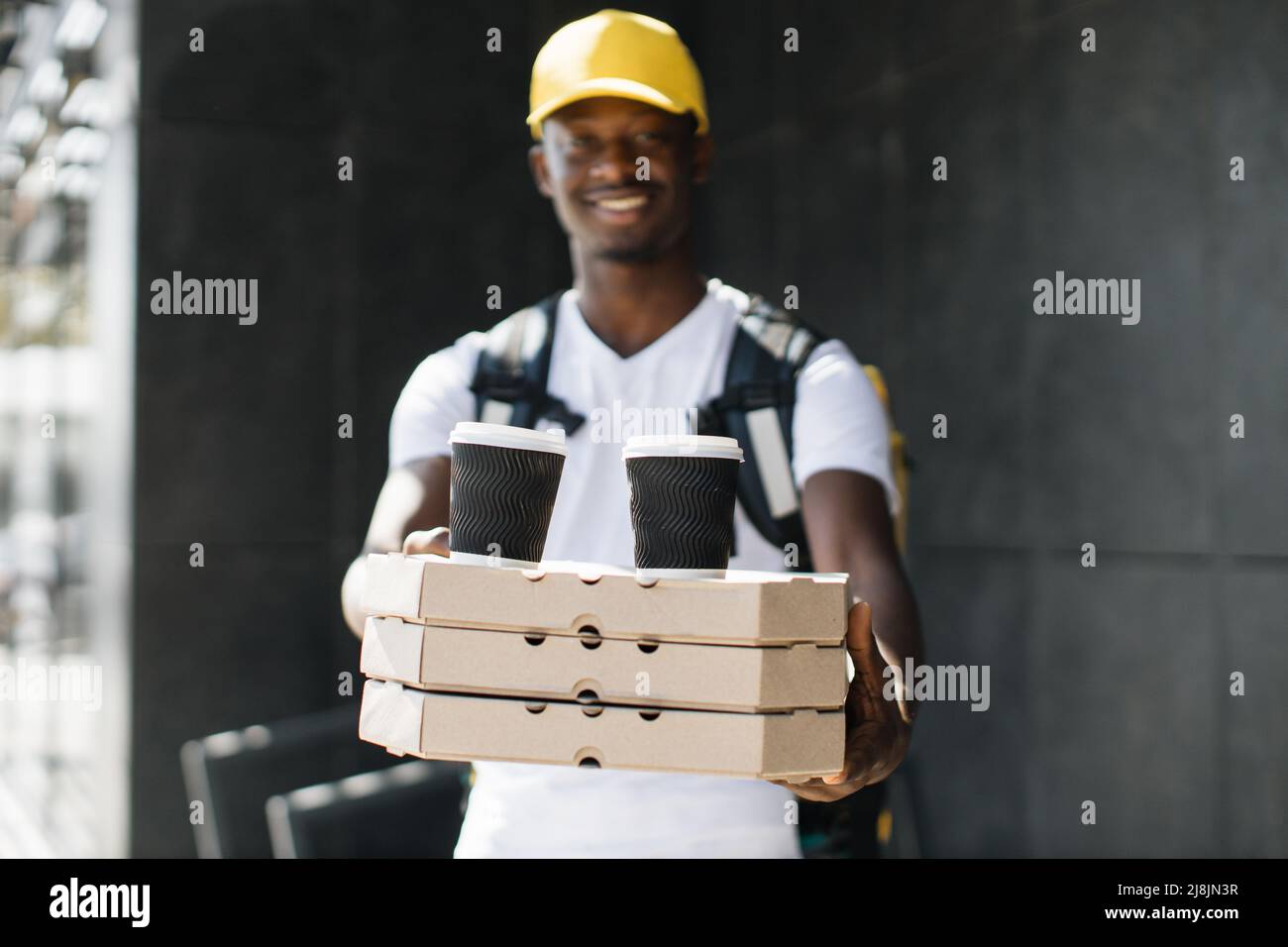 Young happy african delivery man with yellow thermal box backpack and ...