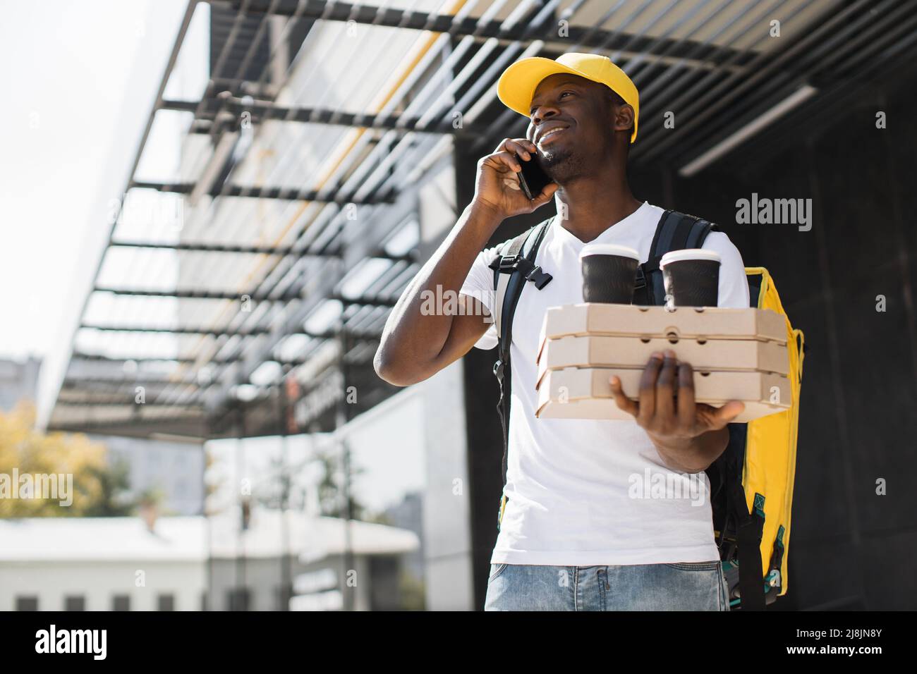 Young African American courier, pizza and coffee delivery man with ...