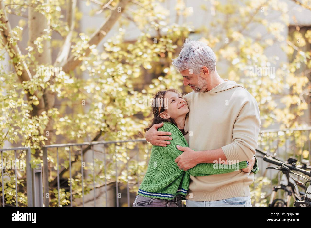 Teenage daughter hugging her father outside in town when spending time ...