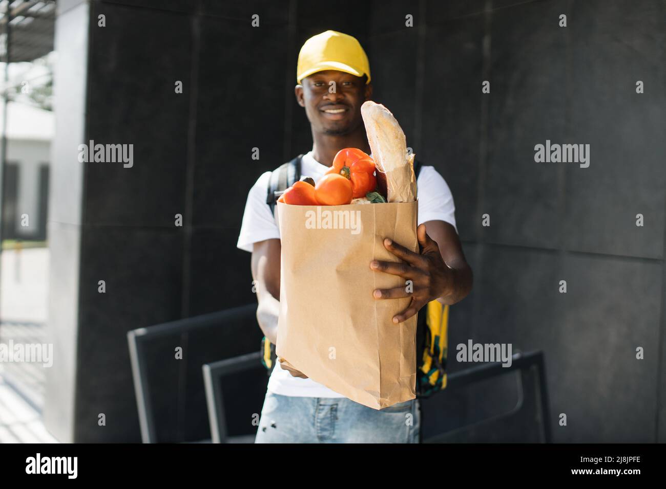 Delivery concept. African American courier standing with a package with ...