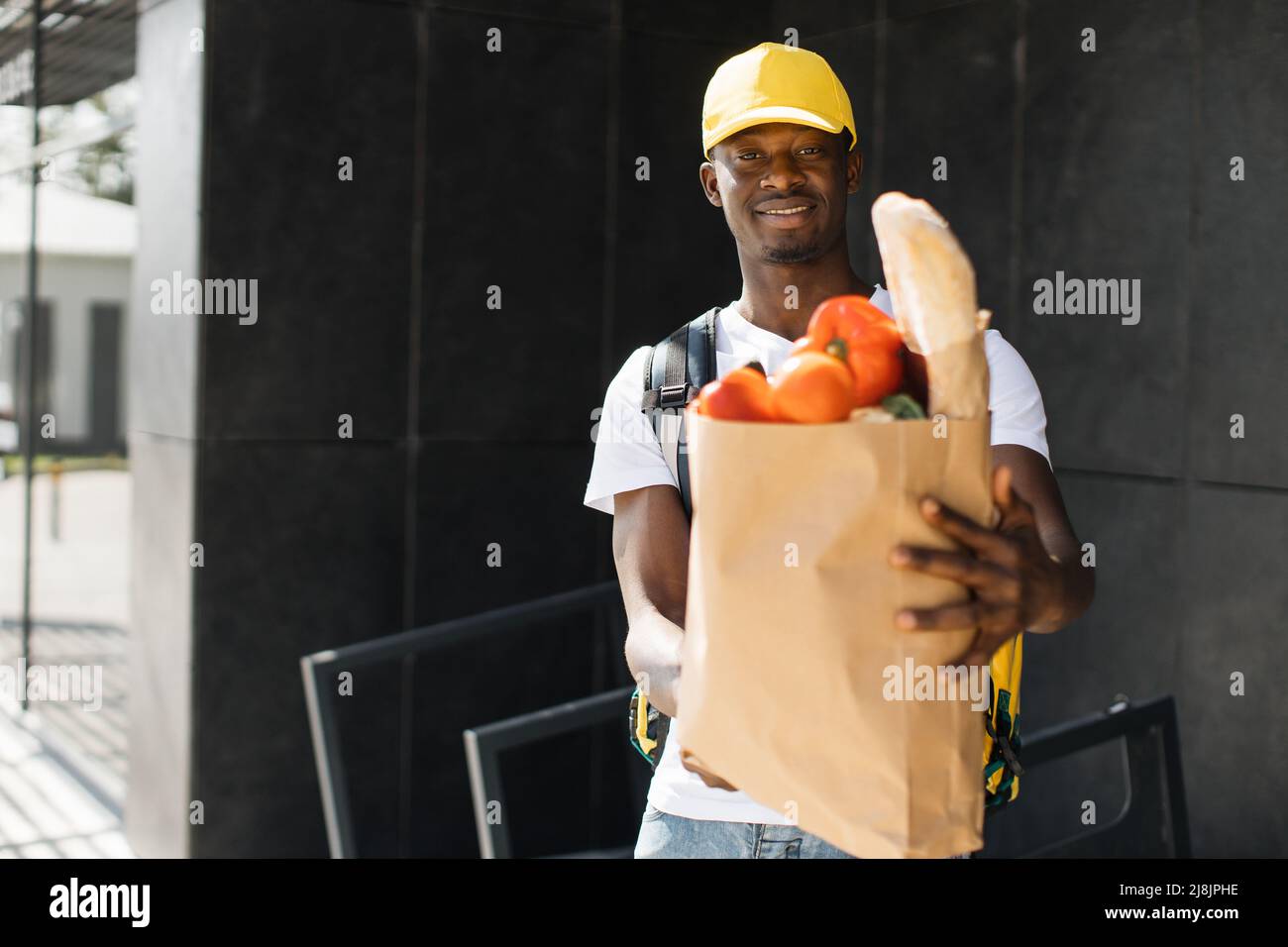 Delivery concept. African American courier standing with a package with ...