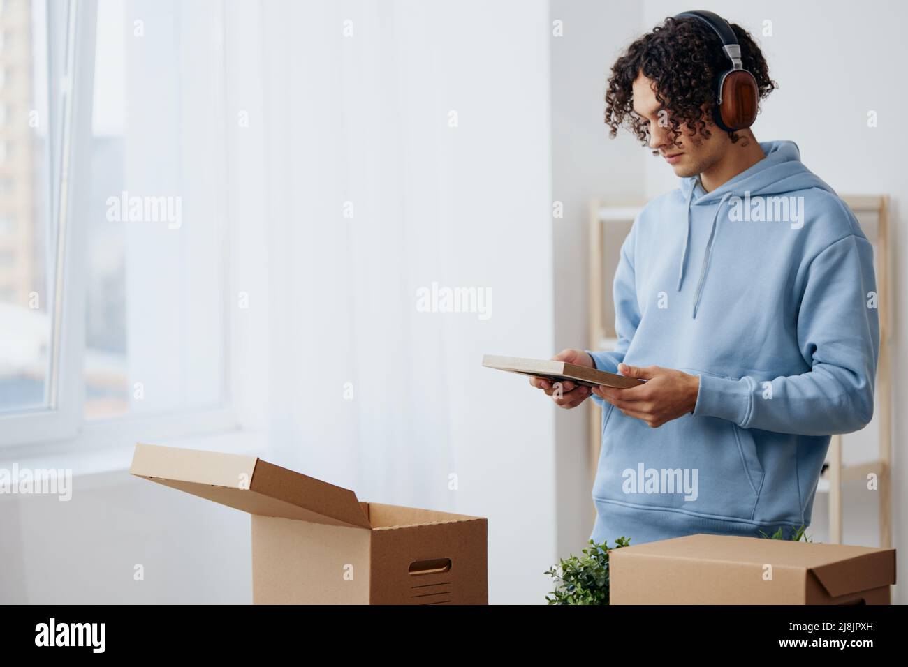 portrait of a man unpacking things from boxes in the room sorting ...