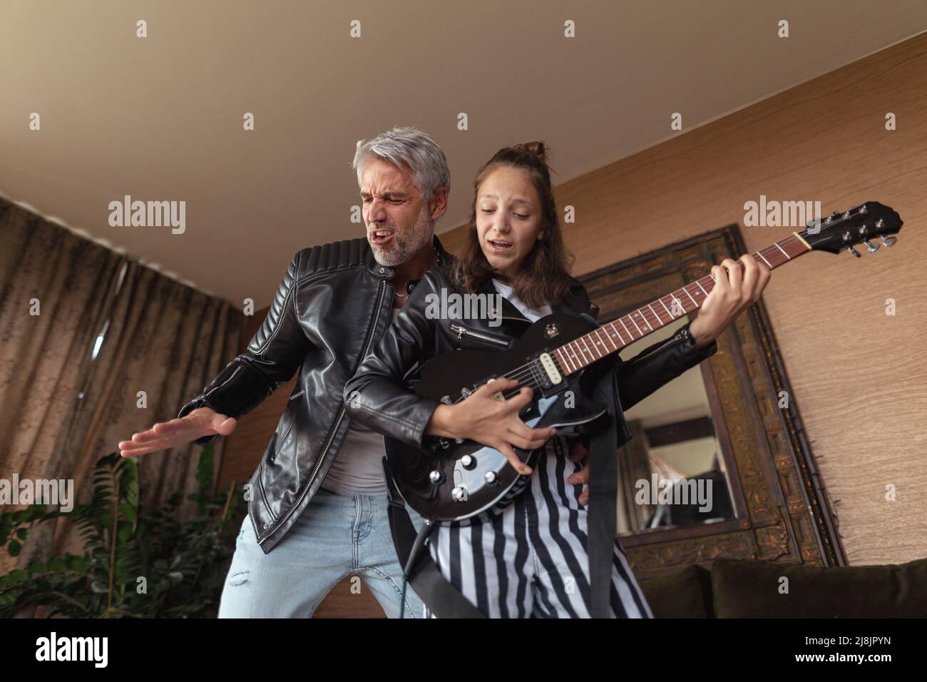 Father rock guitarist having fun and and dancing with his teenage ...