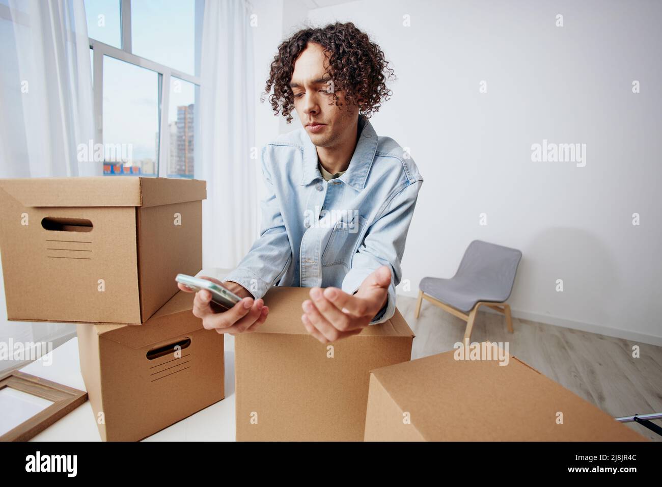 portrait of a man unpacking things from boxes in the room interior ...