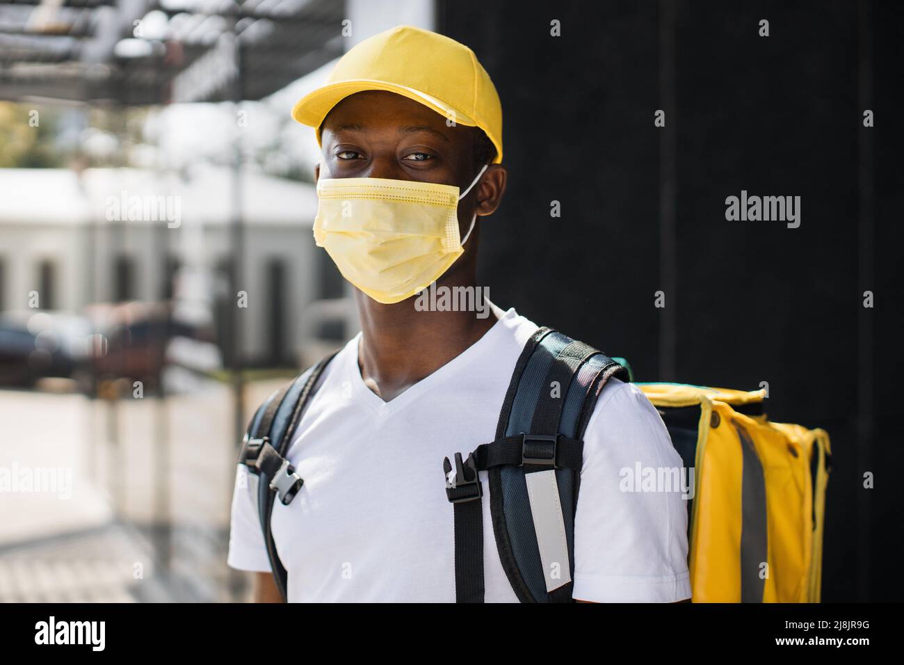 Portrait of delivery man with yellow cap in face mask and thermal ...